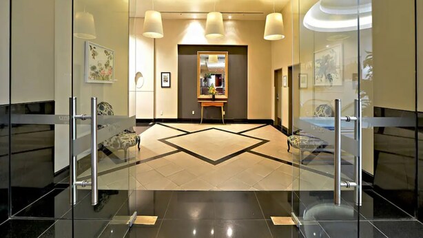 Um lobby de hotel moderno, com divisória de vidro, balcão de recepção e piso com padrão geométrico.