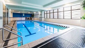 Piscina interior com faixas de natação bem definidas, deck revestido com azulejos e design moderno.