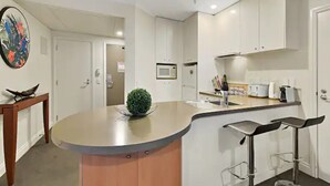 Uma cozinha moderna com uma ilha central, banquetas, micro-ondas e torradeira.