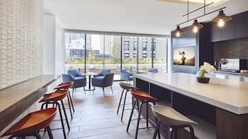 Uma área de bar moderna com taburetes altos, um balcão comprido e iluminação pendente.