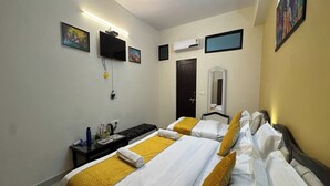 Quarto de hotel com duas camas, uma escrivaninha, uma cadeira, um espelho e obras de arte nas paredes.