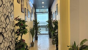 Um corredor com plantas em vasos, quadros nas paredes e iluminação embutida no teto.