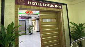 A entrada do Hotel Lotus Inn, com piso de mármore e um tapete vermelho que leva à porta.