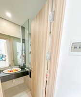 Um banheiro moderno com box de vidro, pia com espelho e porta de madeira.