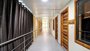 Um corredor com corrimão de metal, portas de madeira e chão de azulejos.