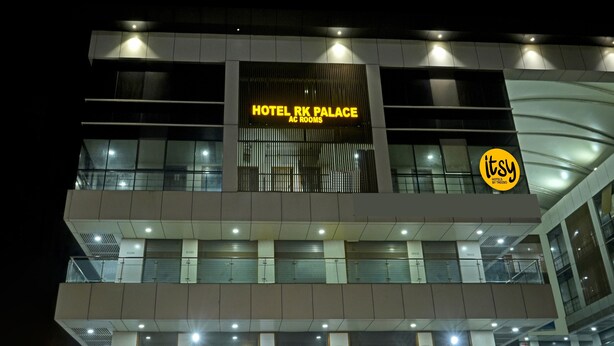 Edifício de hotel com uma placa que diz 'HOTEL RK PALACE AC ROOMS'.
