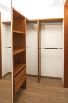 Um closet amplo com prateleiras de madeira e uma barra de metal para pendurar roupas.