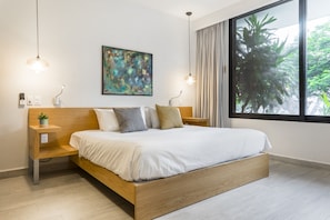Quarto moderno com cama de madeira, mesa lateral, quadro na parede e janela grande com cortinas.