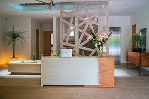 Balcão de atendimento moderno com um laptop, cercado por plantas e um painel decorativo.