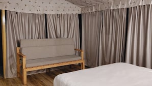 Quarto com um banco de madeira, uma cama e cortinas.