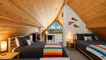 Quarto sótão acolhedor com duas camas, um espaço de refeições e vista para o exterior.