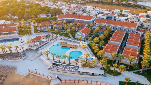 Vista aérea de um resort com uma piscina grande, palmeiras e acesso à praia.