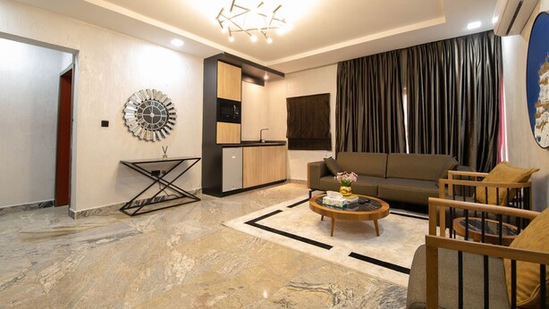 Uma sala de estar moderna com sofá, mesa de centro e um objeto decorativo na parede.