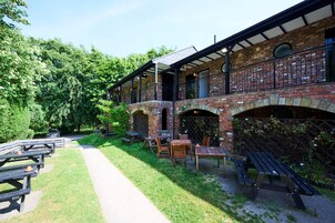 Um edifício de tijolos com mesas ao ar livre e um terraço coberto.