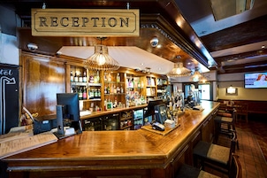 Uma área de recepção com balcão de madeira, bar e diversas garrafas de bebidas.