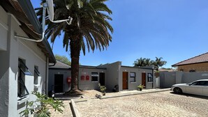 Um bairro residencial com um caminho de pedras, uma palmeira e um carro branco estacionado na rua.