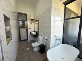 Uma casa de banho moderna com uma banheira branca, sanita e lavatório.