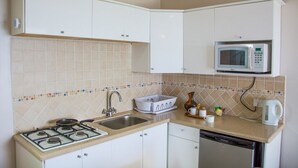 Uma cozinha com armários brancos, fogão a gás, micro-ondas e máquina de lavar louça.