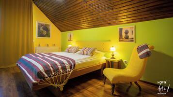 Quarto de hotel com teto de madeira, uma cama com roupa de cama listrada, uma poltrona amarela e duas luminárias fixadas na parede.