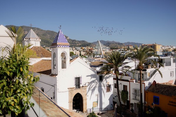 Uma cidade costeira com edifícios brancos, uma igreja com telhado azul e branco, e palmeiras.