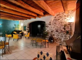 Um interior acolhedor com parede de pedra, vigas de madeira no teto e cadeiras amarelas.