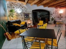 Uma sala de estar acolhedora com um sofá preto, cadeiras amarelas, uma mesa de jantar e uma guitarra.