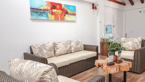 Uma sala de estar com sofá, duas poltronas, uma mesa de centro e um quadro na parede.