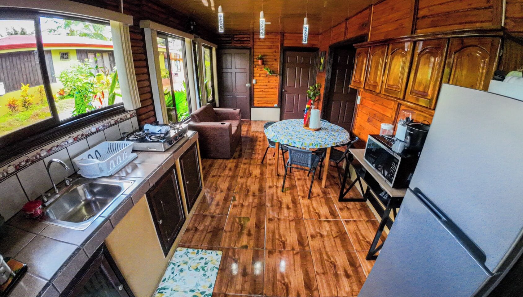 Uma cozinha compacta com área de jantar, piso de madeira e vista pela janela.