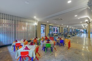 Uma ampla sala de jantar com várias mesas e cadeiras, janelas grandes e um interior limpo e bem iluminado.