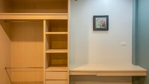 Quarto com guarda-roupa de madeira, escrivaninha e um quadro na parede.