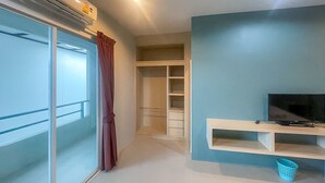Quarto moderno com porta de vidro deslizante, armário embutido, TV em prateleira branca e luminária no teto.