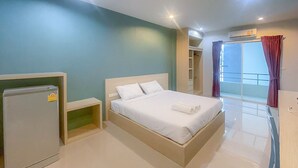 Quarto de hotel com uma cama, uma pequena mesa de escritório, um guarda-roupa e varanda com vista.