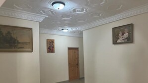 Um corredor com porta de madeira, duas obras de arte emolduradas nas paredes e luminária embutida no teto.