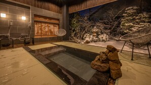 Área de spa com hidromassagem, paredes de madeira e um mural com tema de inverno.