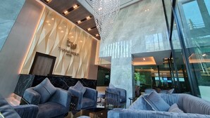 Um lobby moderno com um candelabro, área de estar e balcão de recepção.