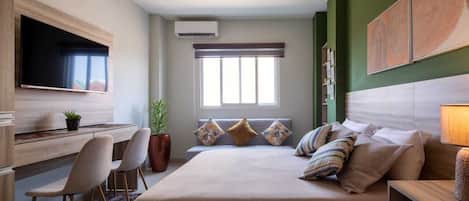 Quarto de hotel moderno com uma cama grande, uma escrivaninha com televisão de tela plana, uma janela com persianas e uma parede de destaque verde.