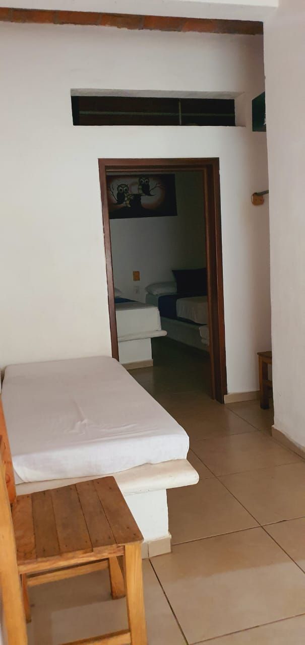 Um quarto com uma cama, uma mesa de madeira e uma porta que dá para outro quarto com uma cama.