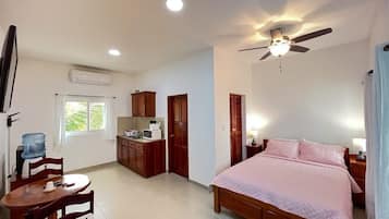 Quarto com cama, mesas de cabeceira, ventoinha no teto e janela.