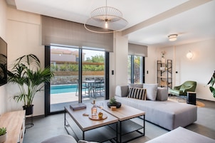 Uma sala de estar moderna com sofá, mesa de centro e vista para uma piscina.
