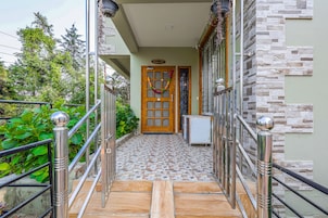Um corredor com piso de azulejos, porta de madeira com painel de vidro e um pequeno armário branco.
