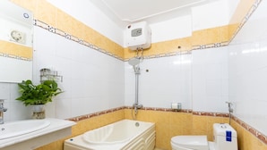 Casa de banho com banheira, sanita, lavatório e termo.