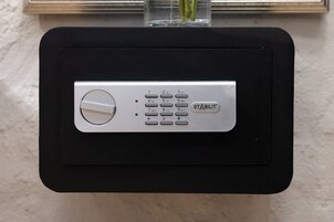 Dispositivo eletrônico preto com teclado e um botão de controle, fixado na parede.