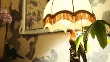 Uma luminária com base decorativa e cúpula branca com franjas, colocada em uma estante.