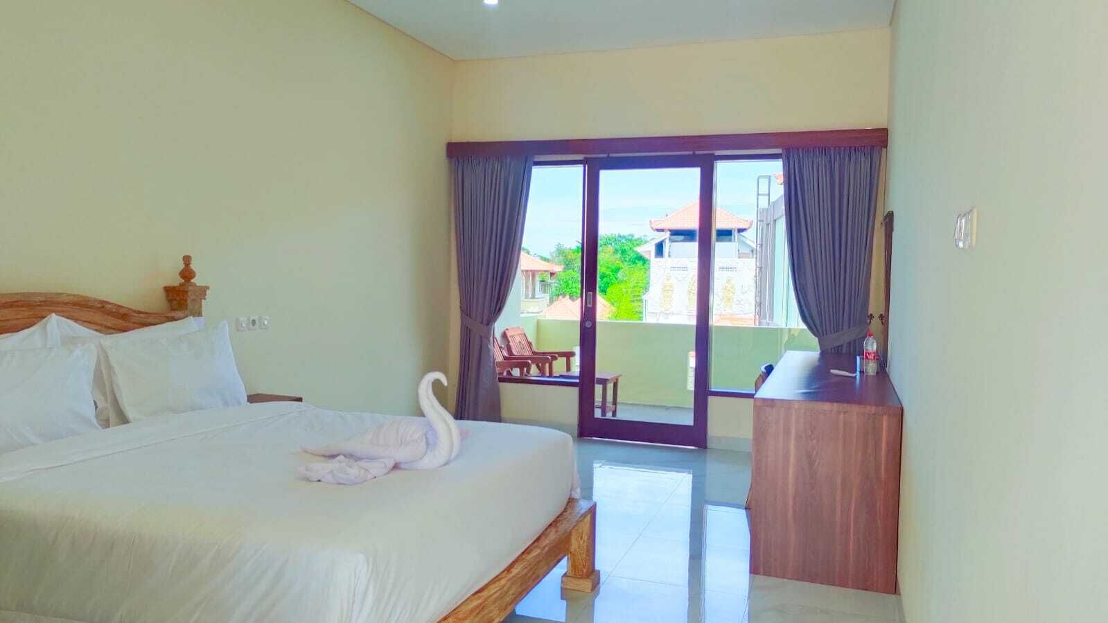 Quarto de hotel com cama, cabeceira de madeira, escrivaninha e vista para o exterior.