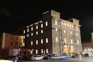 Um edifício histórico com vários andares e uma torre central, com uma série de janelas e uma entrada imponente.