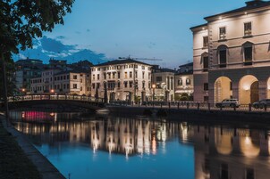Um rio calmo com uma ponte, edifícios históricos e uma rua bem iluminada.