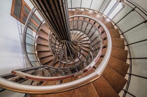 Uma escadaria em espiral com corrimão de metal e degraus de madeira.