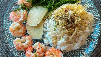 Prato com camarão, arroz e vegetais sobre um tapete texturizado.