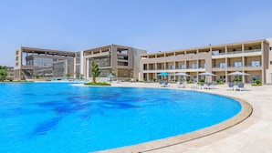 Um hotel moderno com uma piscina grande, várias varandas e espreguiçadeiras.