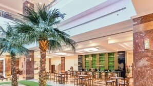 Um hall amplo com área de estar central, um bar e uma parede verde com a placa 'Lobby'.
